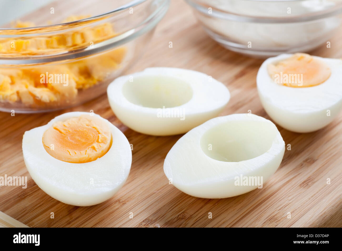 Two hard boiled eggs cut in half with yolk in bowl Stock Photo - Alamy