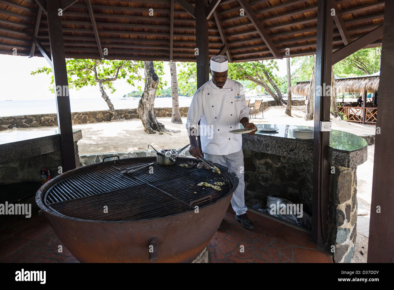 Hotel chef cooks fish on a large barbeque alongside the beach in St ...