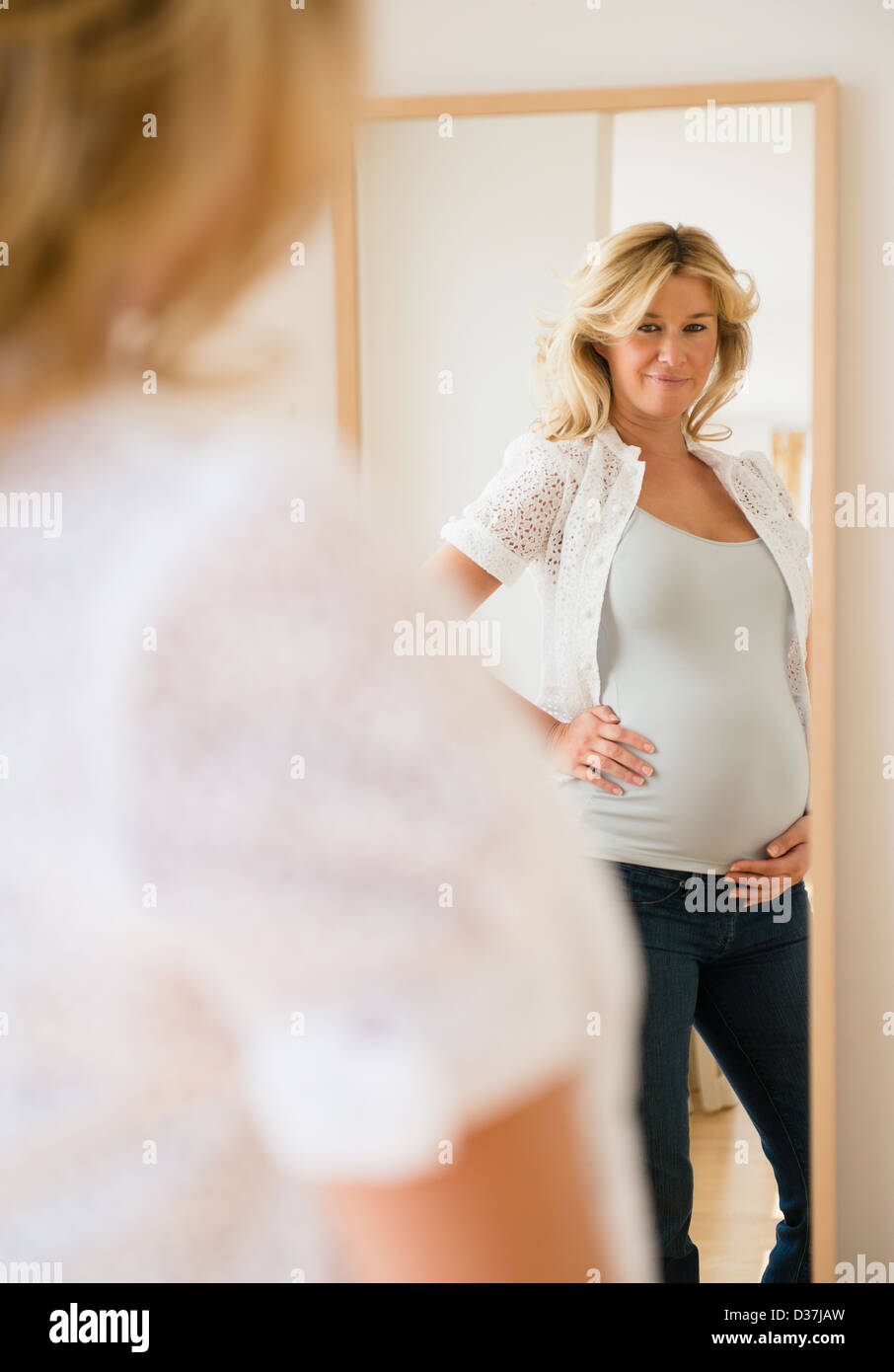 Pregnant woman looking in mirror Stock Photo - Alamy
