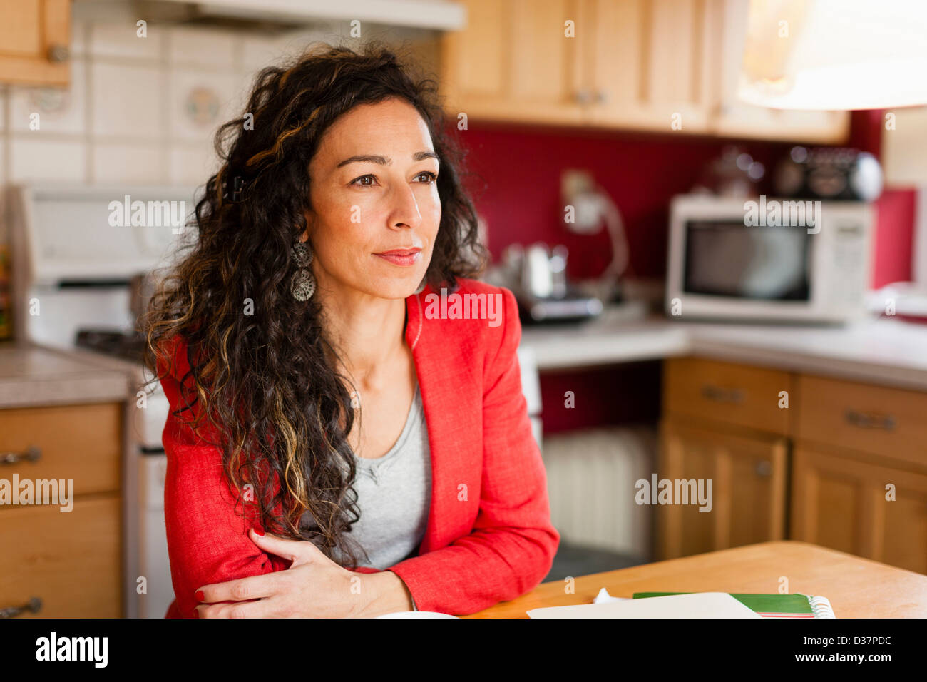 Smiling woman sitting in kitchen Stock Photo - Alamy