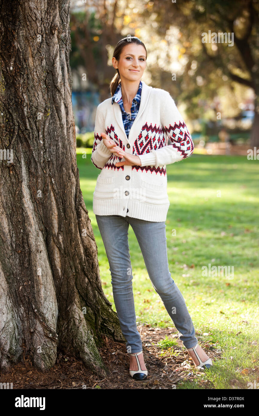 Smiling woman standing by tree Stock Photo - Alamy