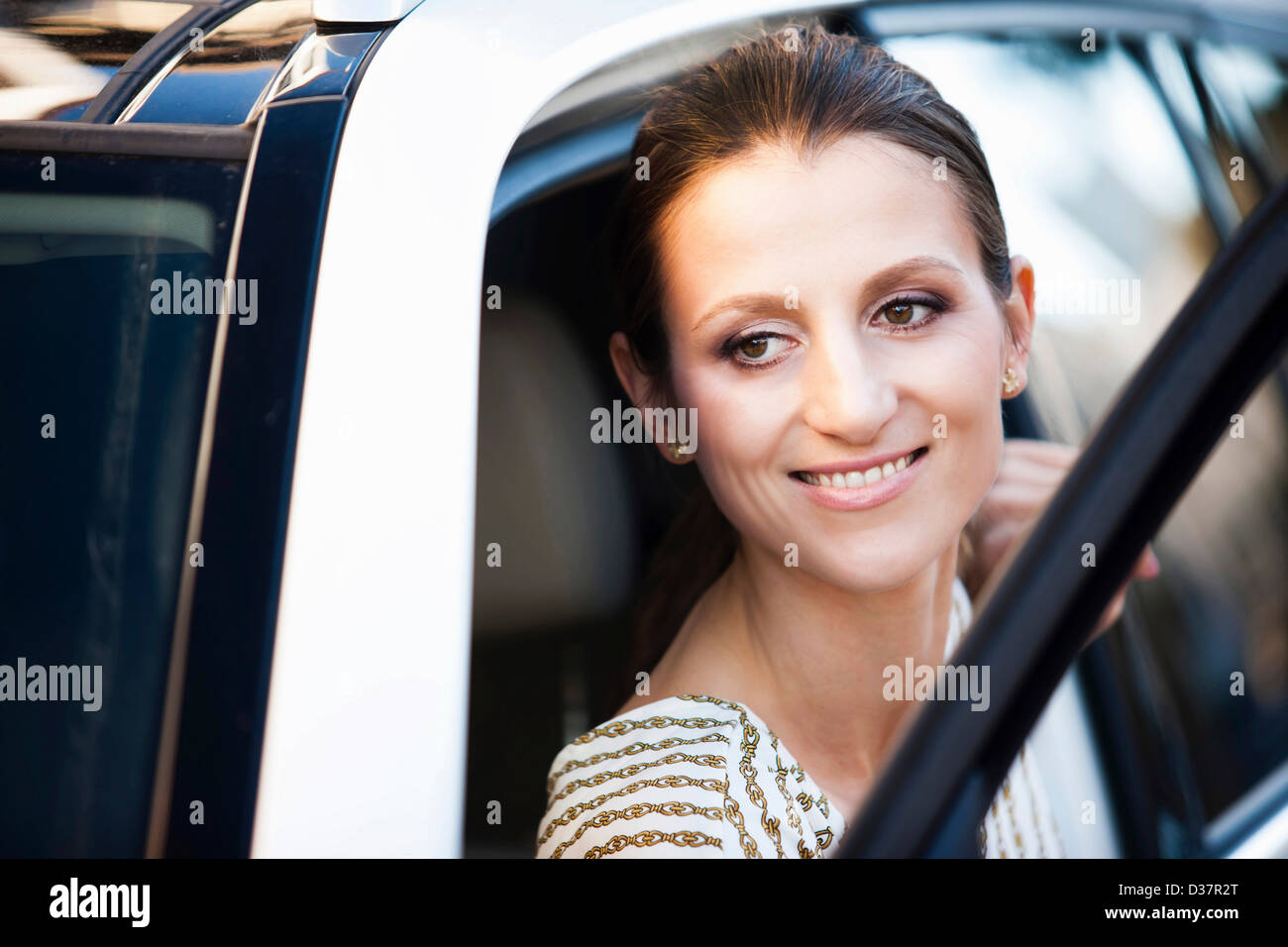 Woman climbing out of car Stock Photo - Alamy