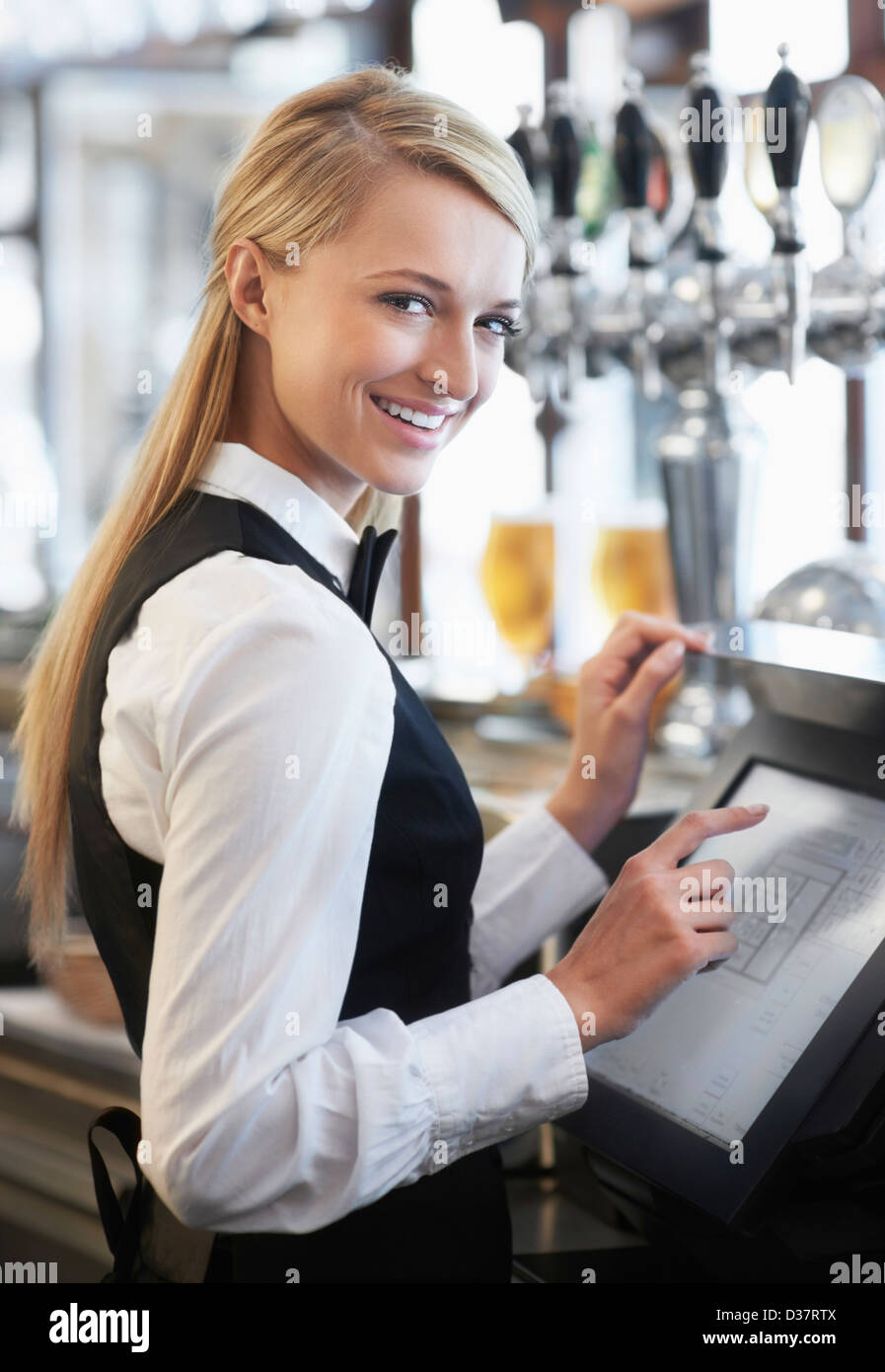 Denmark, Aarhus, Young waitress using computer at restaurant counter ...