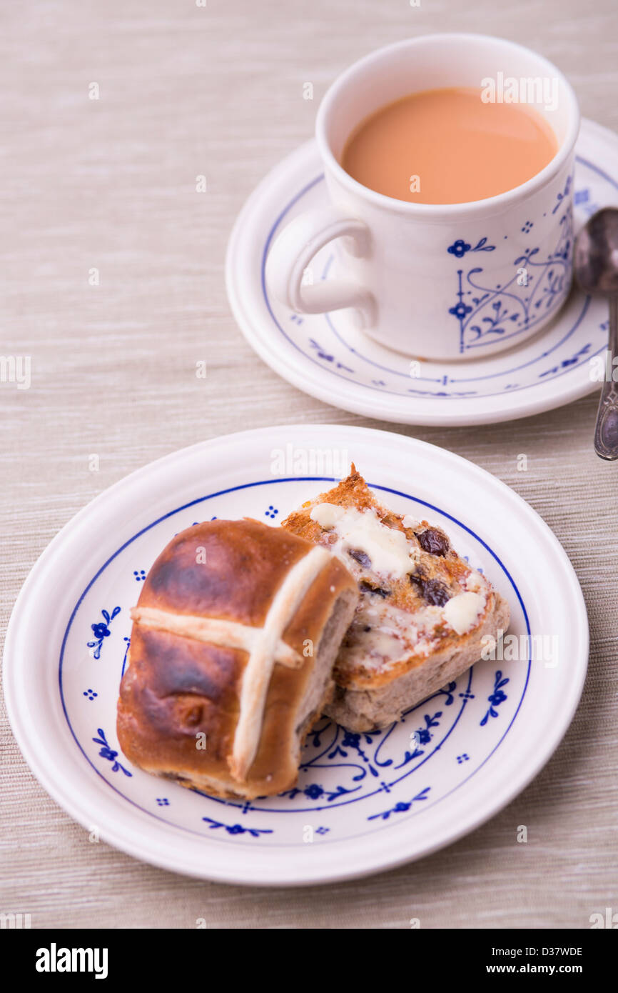 Toasted hot cross bun buttered with a cup of tea served on patterned ...