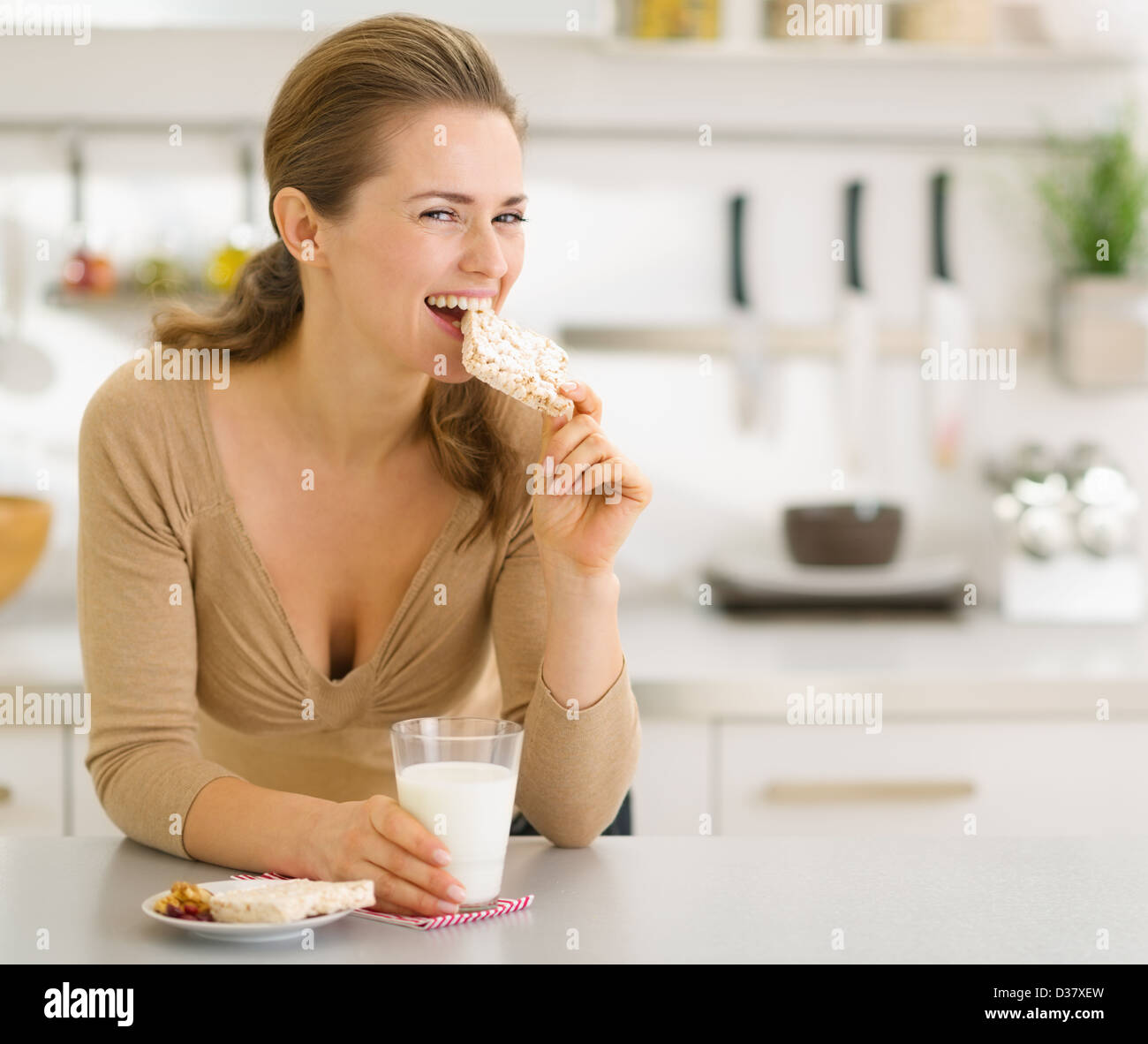 Young woman eating snacks in modern kitchen Stock Photo - Alamy