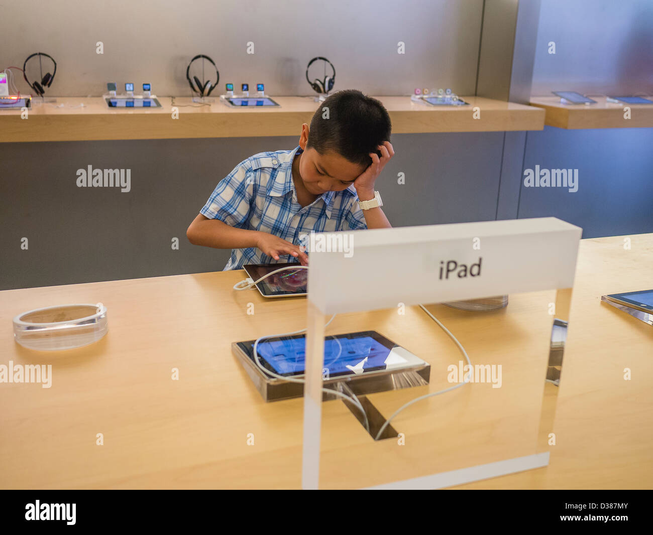 A 7-9 year old Asian boy is engrossed in a computer game on an iPad in ...
