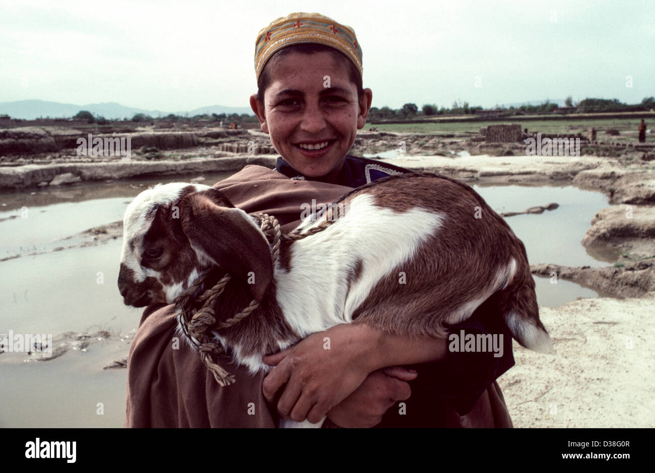 Afghan refugee boy with a young goat in his arms. Refugee Camp ...