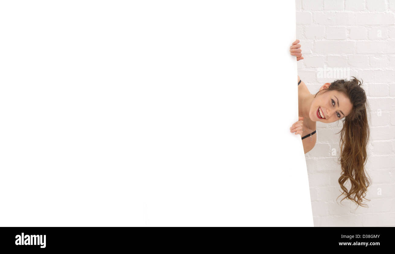 Girl pops head around white backdrop Stock Photo - Alamy