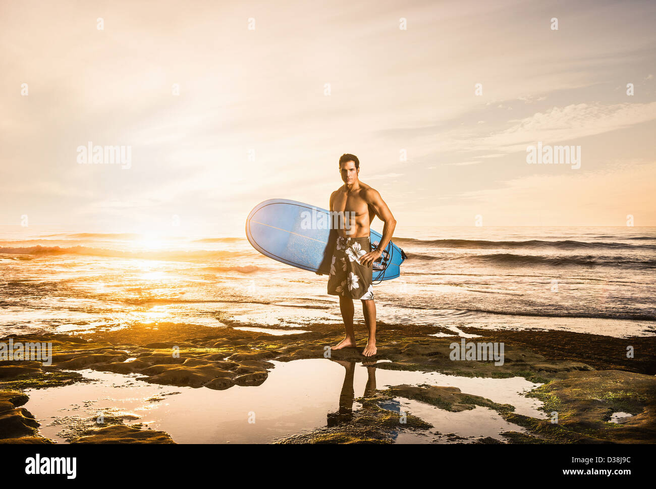 Man carrying surfboard on rocky beach Stock Photo - Alamy