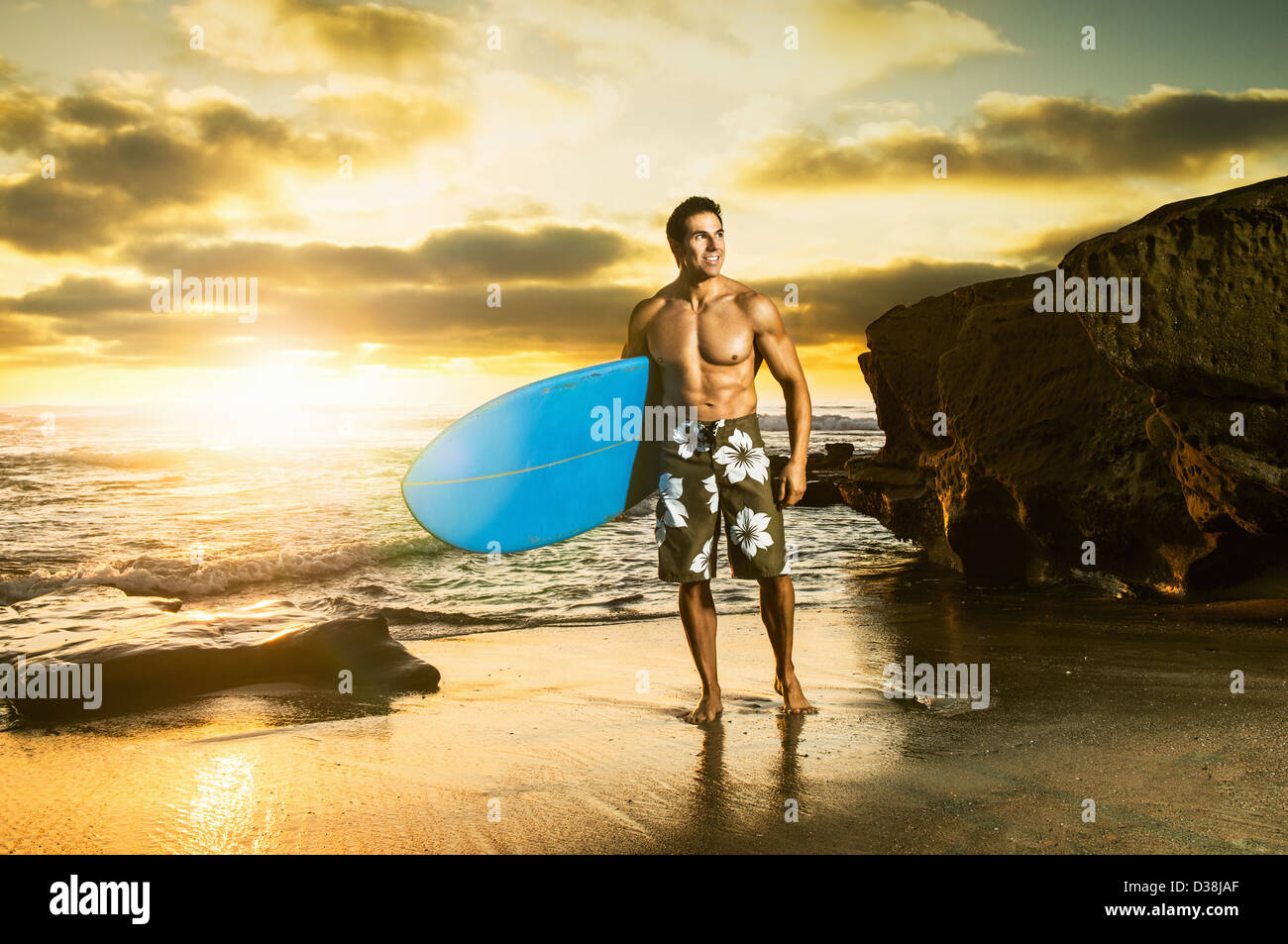 Man carrying surfboard on rocky beach Stock Photo - Alamy