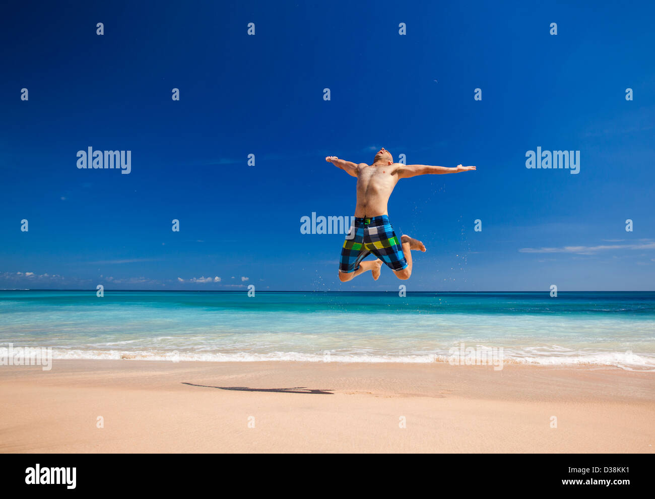 Athletic young man enjoying the summer, jumping in a tropical beach ...