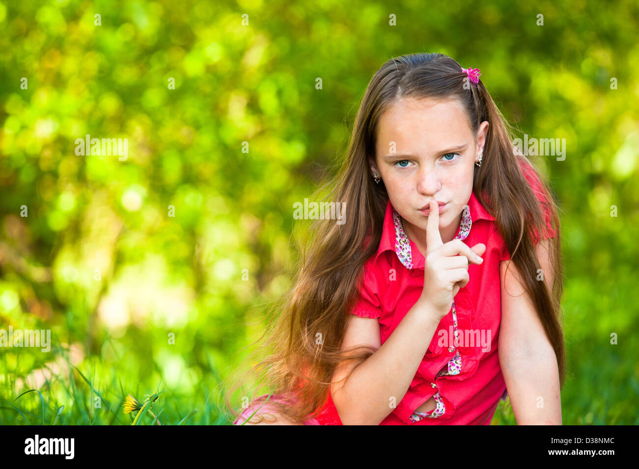 Young girl with her finger over her mouth, hushing Stock Photo - Alamy