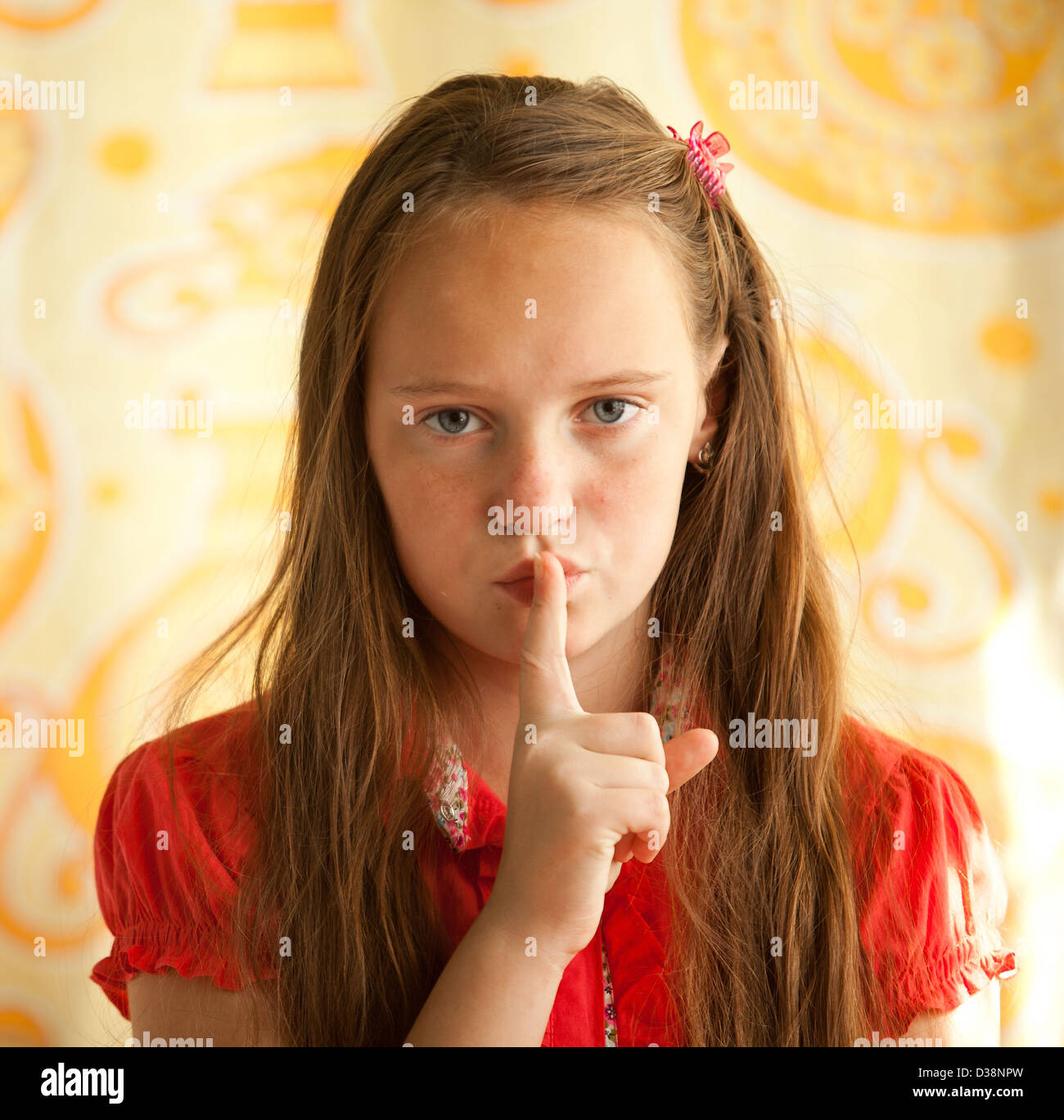 Young girl with her finger over her mouth, hushing Stock Photo - Alamy