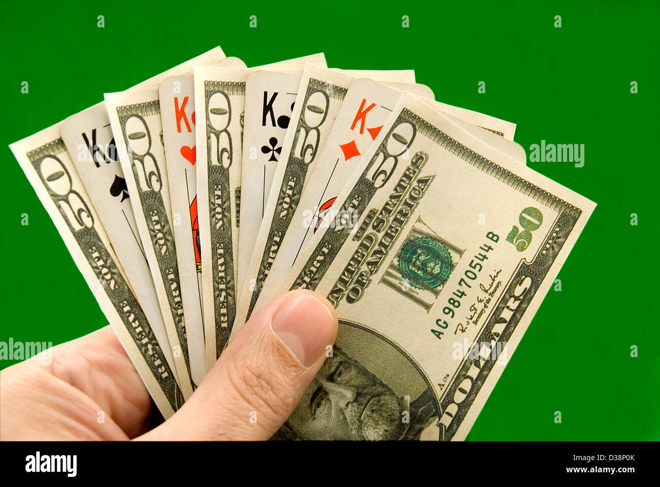 Playing cards and fifty - dollar denominations on a green background ...
