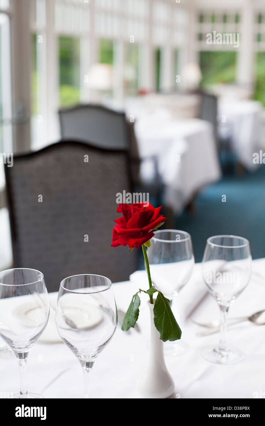 A red rose on a restaurant table set for a romantic meal in an all ...