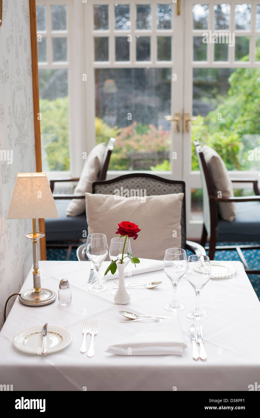 A red rose on a restaurant table set for a romantic meal in an all ...