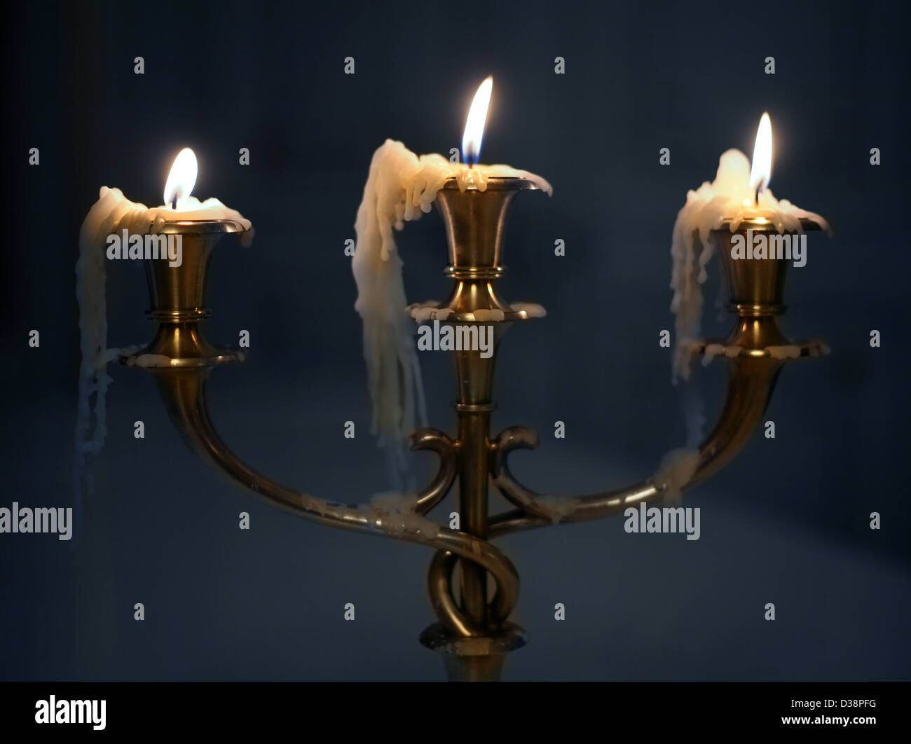 Three burning candles in an ancient gold candelabrum Stock Photo - Alamy