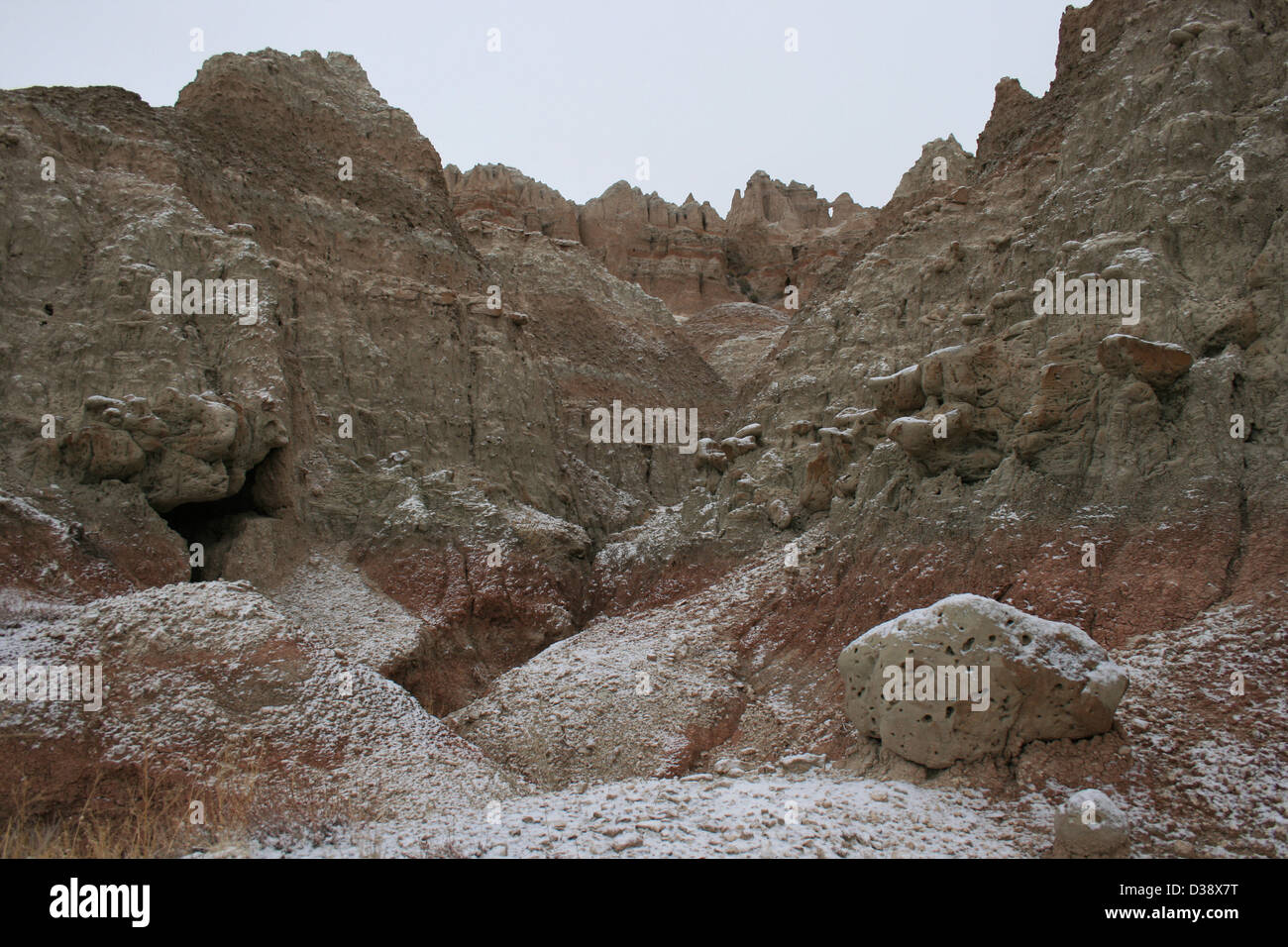 Snow covers the rugged rock formations and caves of Badlands National ...