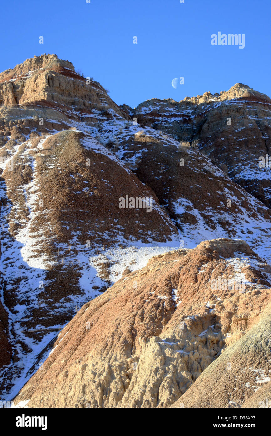 A waning moon sets over the snowy landscape of Badlands National Park ...