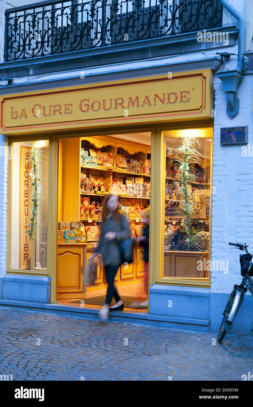 Woman stepping out of La Cure Gourmande candy store, Bruges, Belgium ...