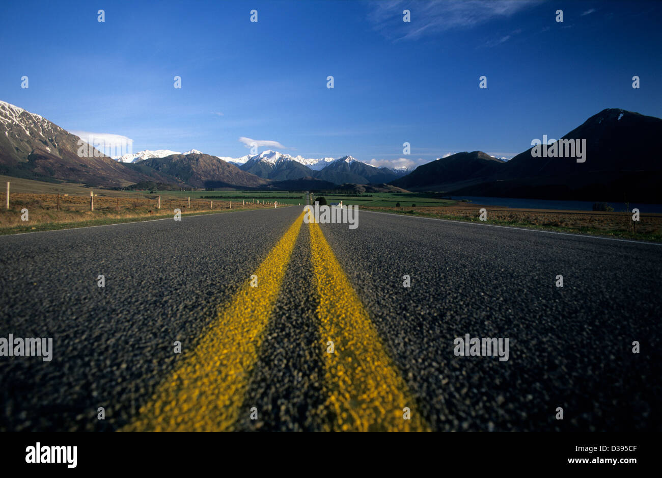 New Zealand, yellow lines on open road leading to mountains Stock Photo ...