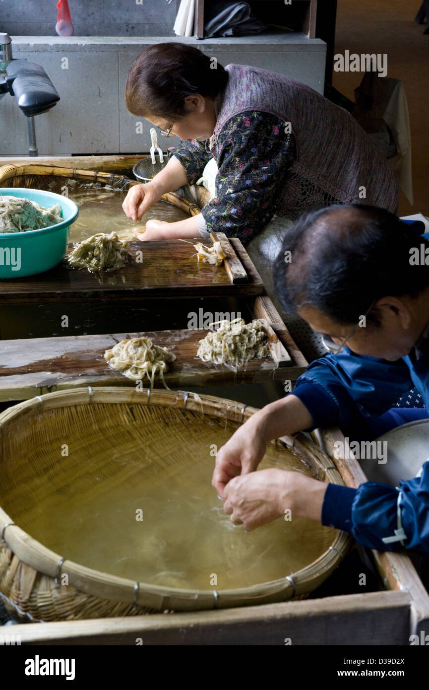 Woman and man sorting mulberry bark fibers by hand in a sink, called ...