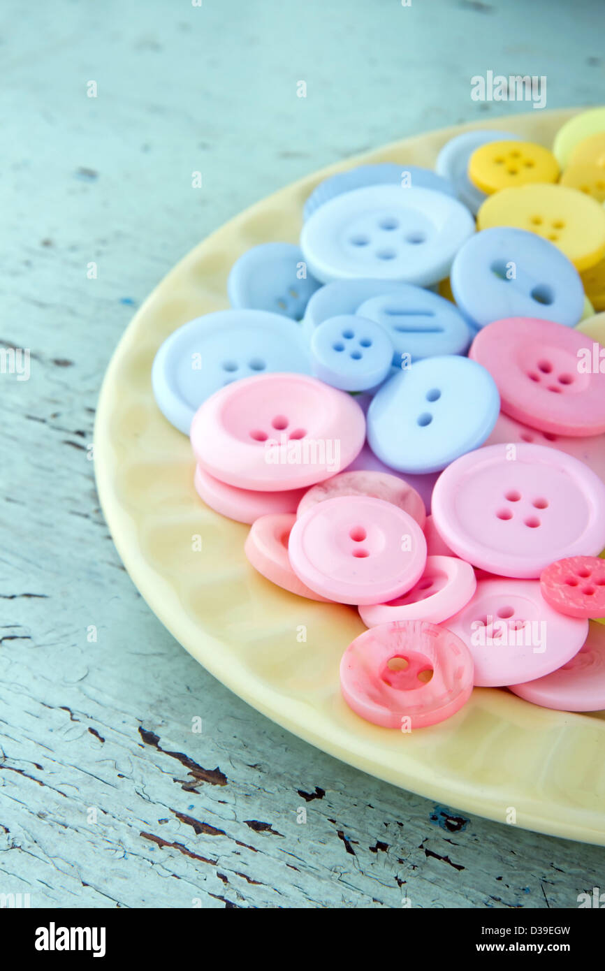 Pink and blue buttons on a light yellow plate on rustic wooden ...