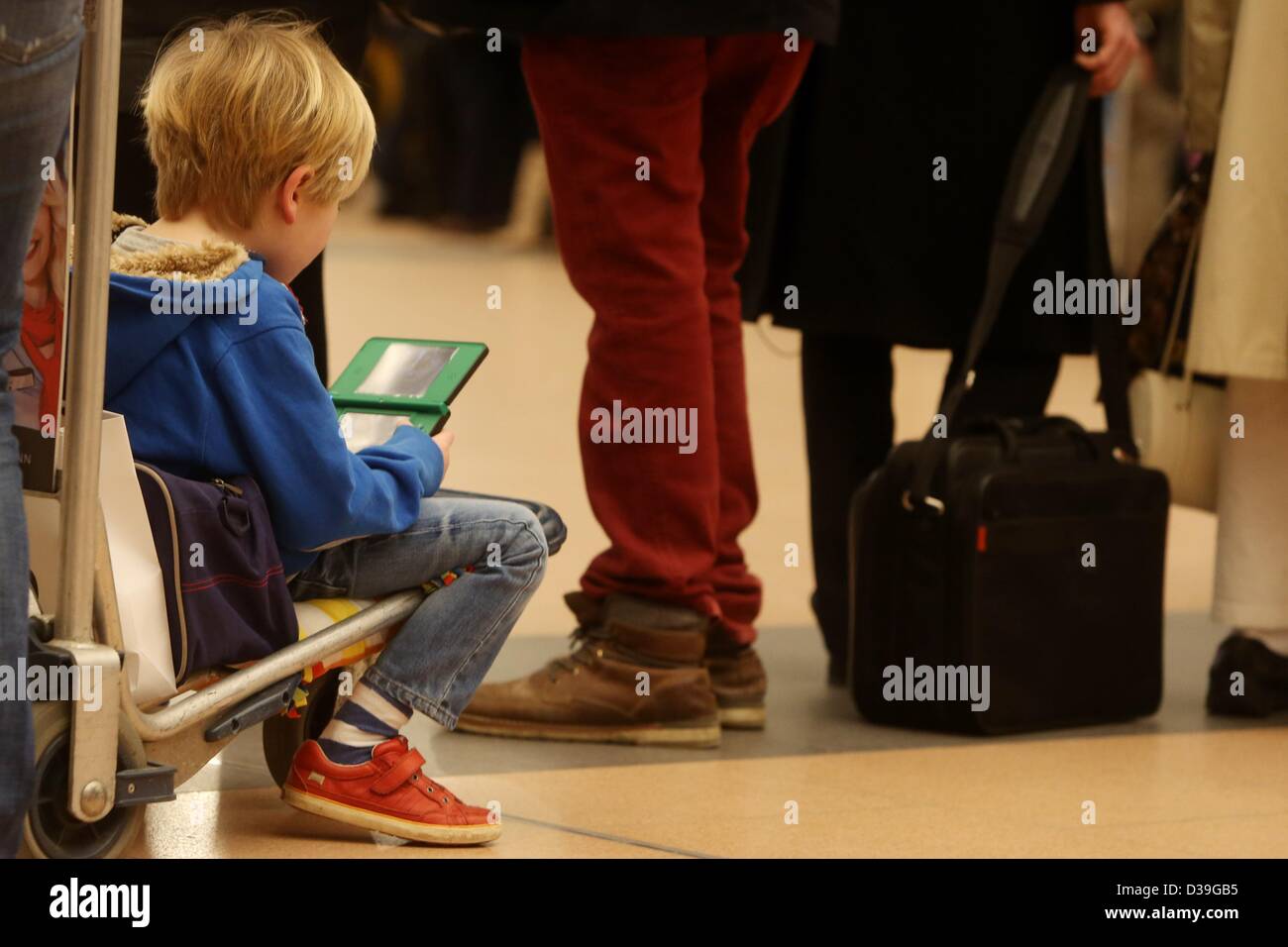 A little boy waits as passengers queue at the security check at the ...