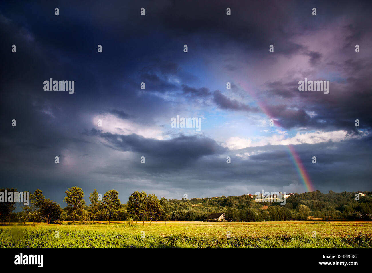 Natural rainbow over green field and dark sky Stock Photo - Alamy