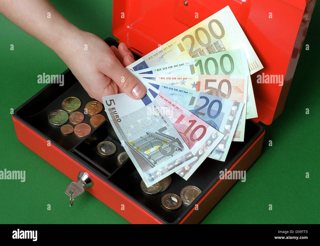 A cashbox containing Euro coins and a hand holding six of the seven new ...