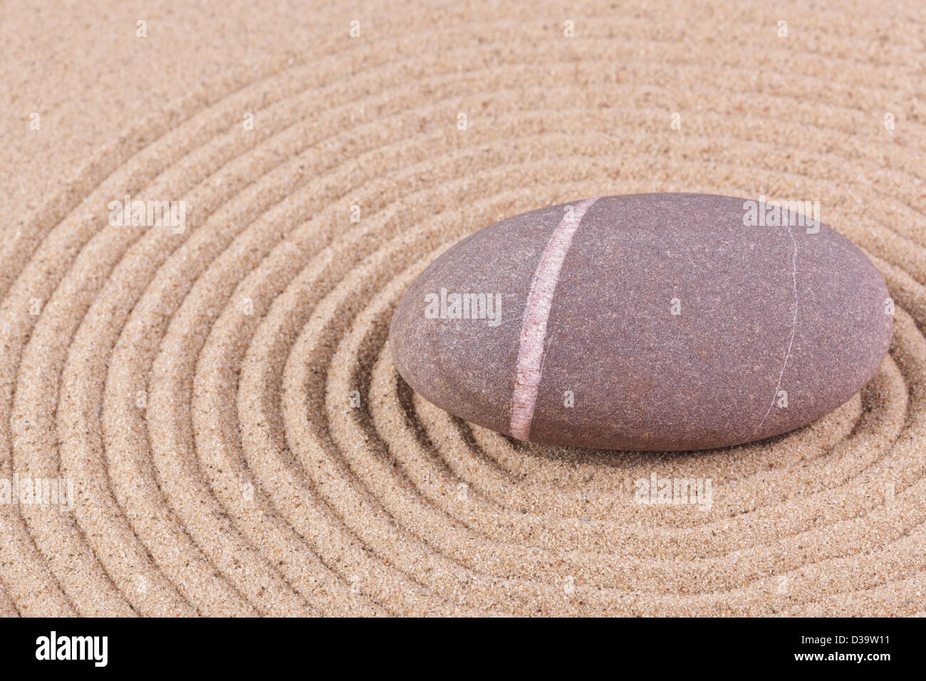 A single pebble in a raked sand circle zen garden Stock Photo - Alamy