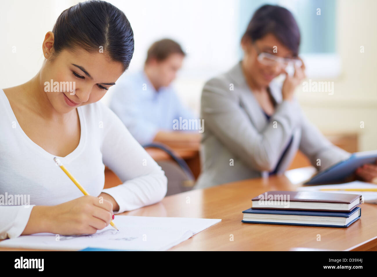 Portrait of pretty girl sitting in college library and making notes ...