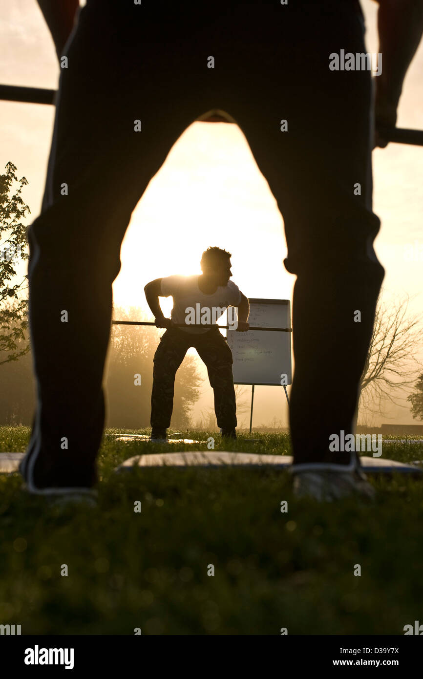 Fitness instructor leading weight lifting class at luxury boot camp ...