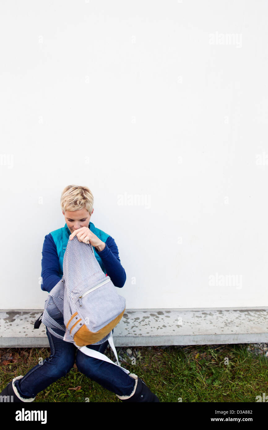 Woman digging through backpack Stock Photo - Alamy