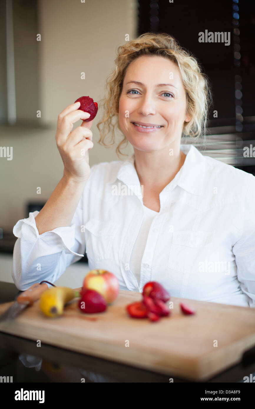 Woman eating fruit in kitchen Stock Photo - Alamy