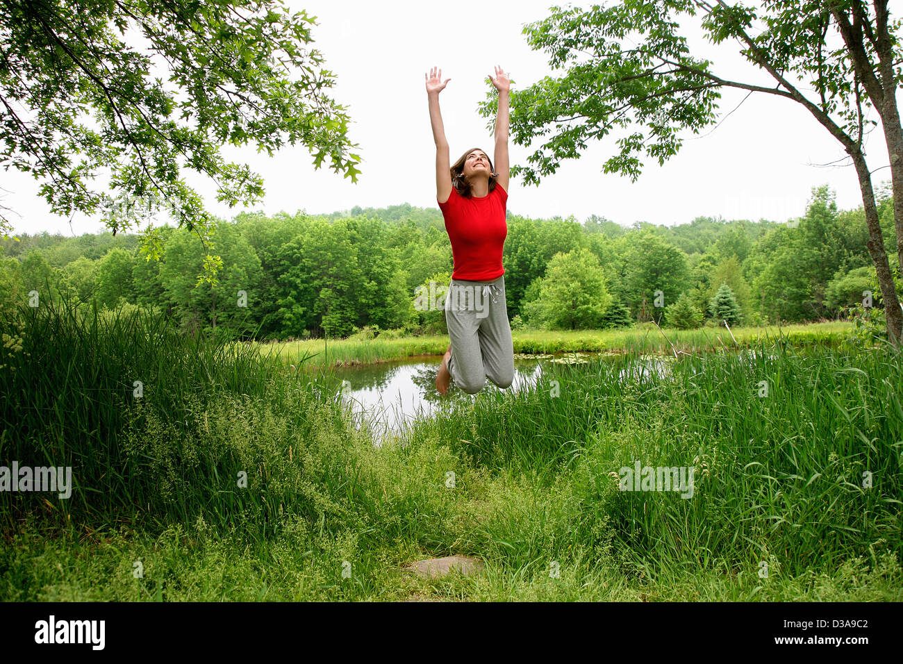 Woman jumping by rural lake Stock Photo - Alamy