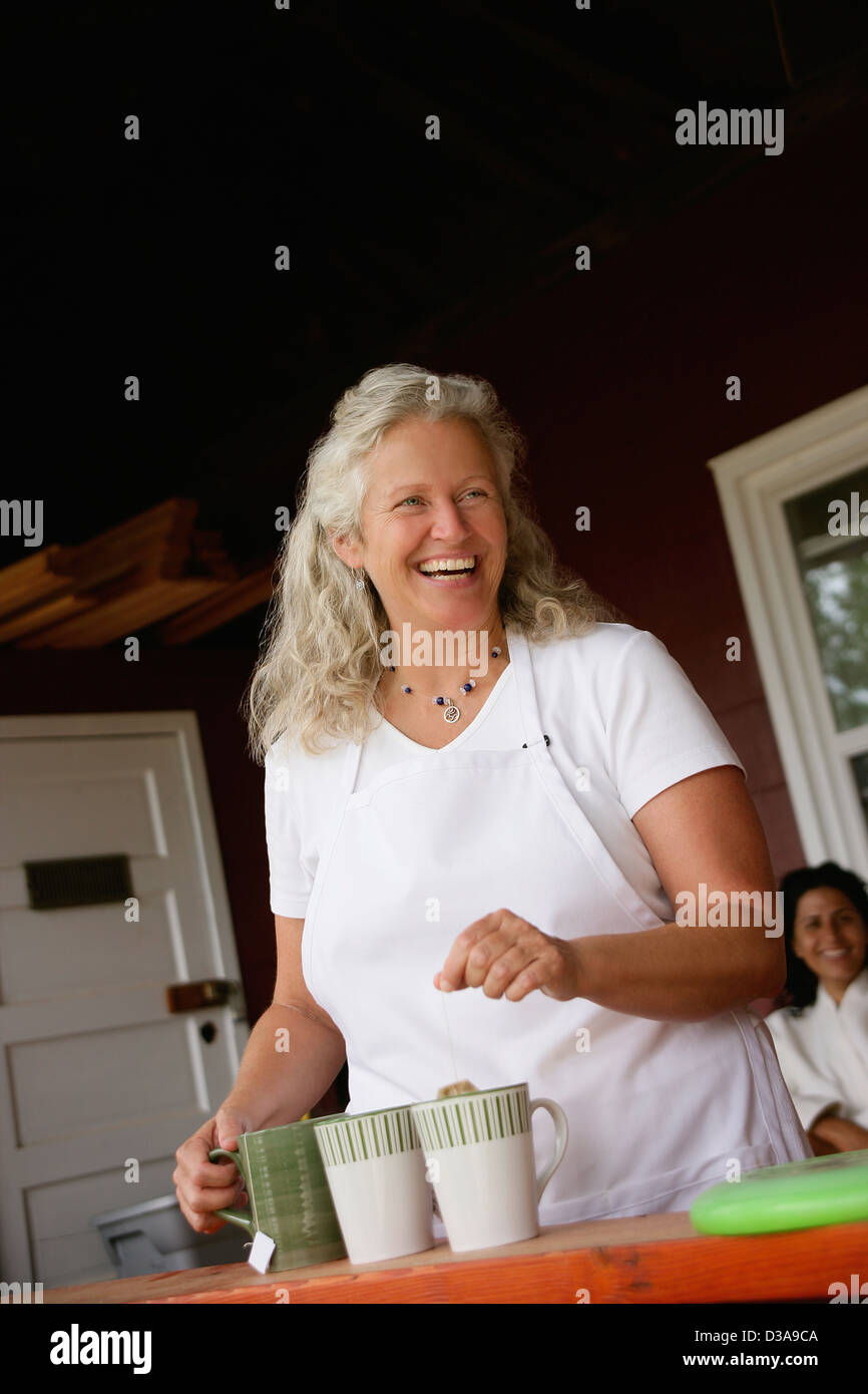 Laughing woman making cups of tea Stock Photo - Alamy