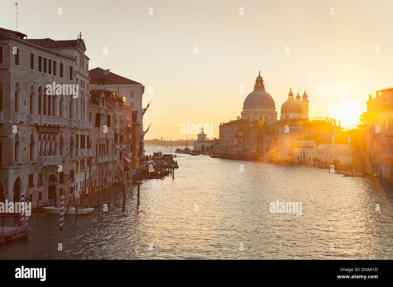 Sun setting over city buildings on canal Stock Photo - Alamy