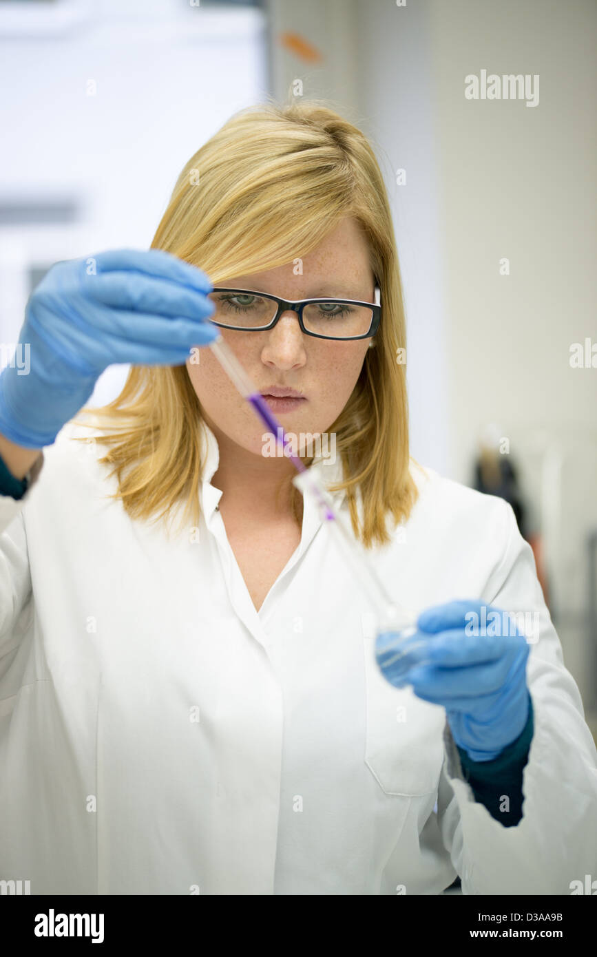 young female scientist in university laboratory works with colorful ...