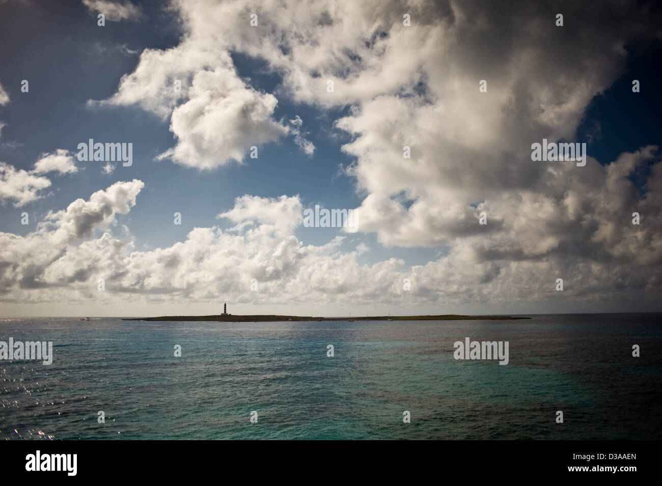View of the lighthouse at Punta Prima with Clouds and sun above the sea ...