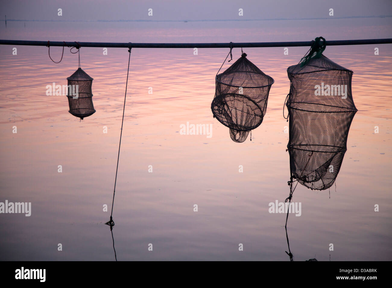 Silhouette of fishing nets over still water Stock Photo - Alamy