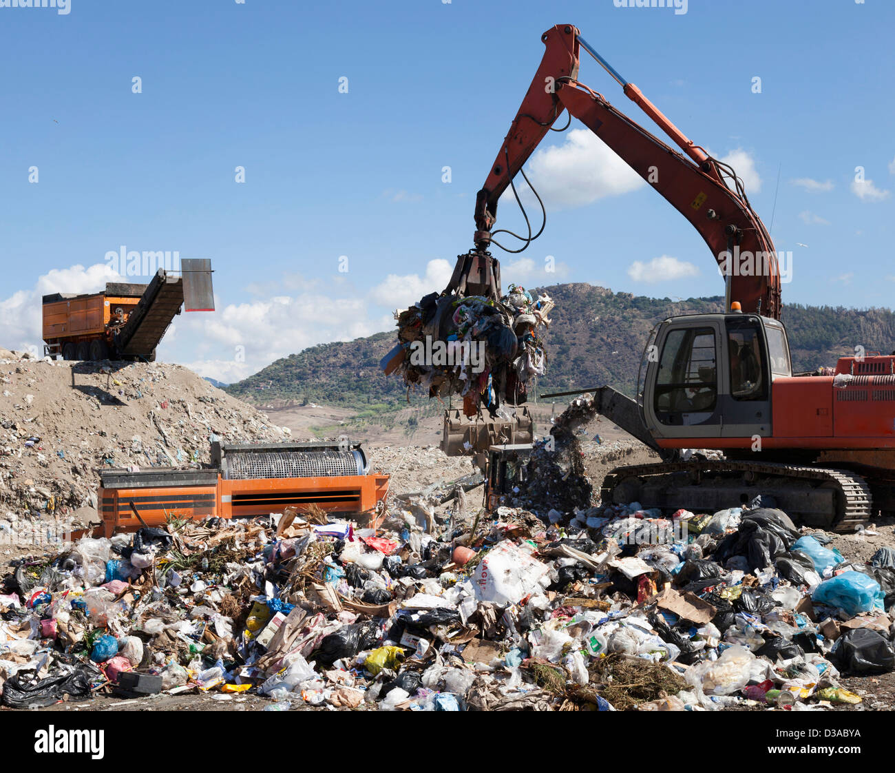 Machinery grabbing waste in landfill Stock Photo - Alamy