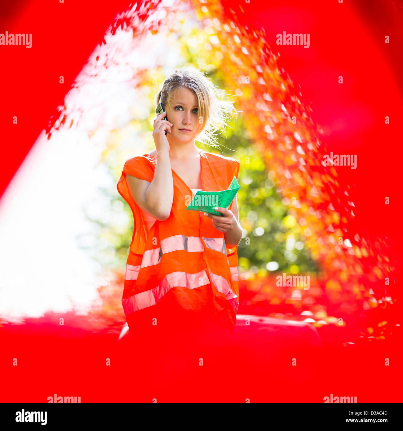 Young female driver wearing a high visibility vest, calling the ...