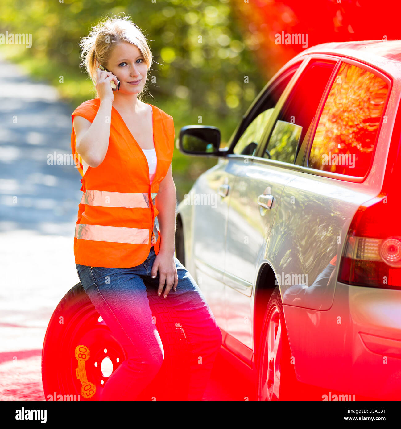 Young female driver wearing a high visibility vest, calling the ...