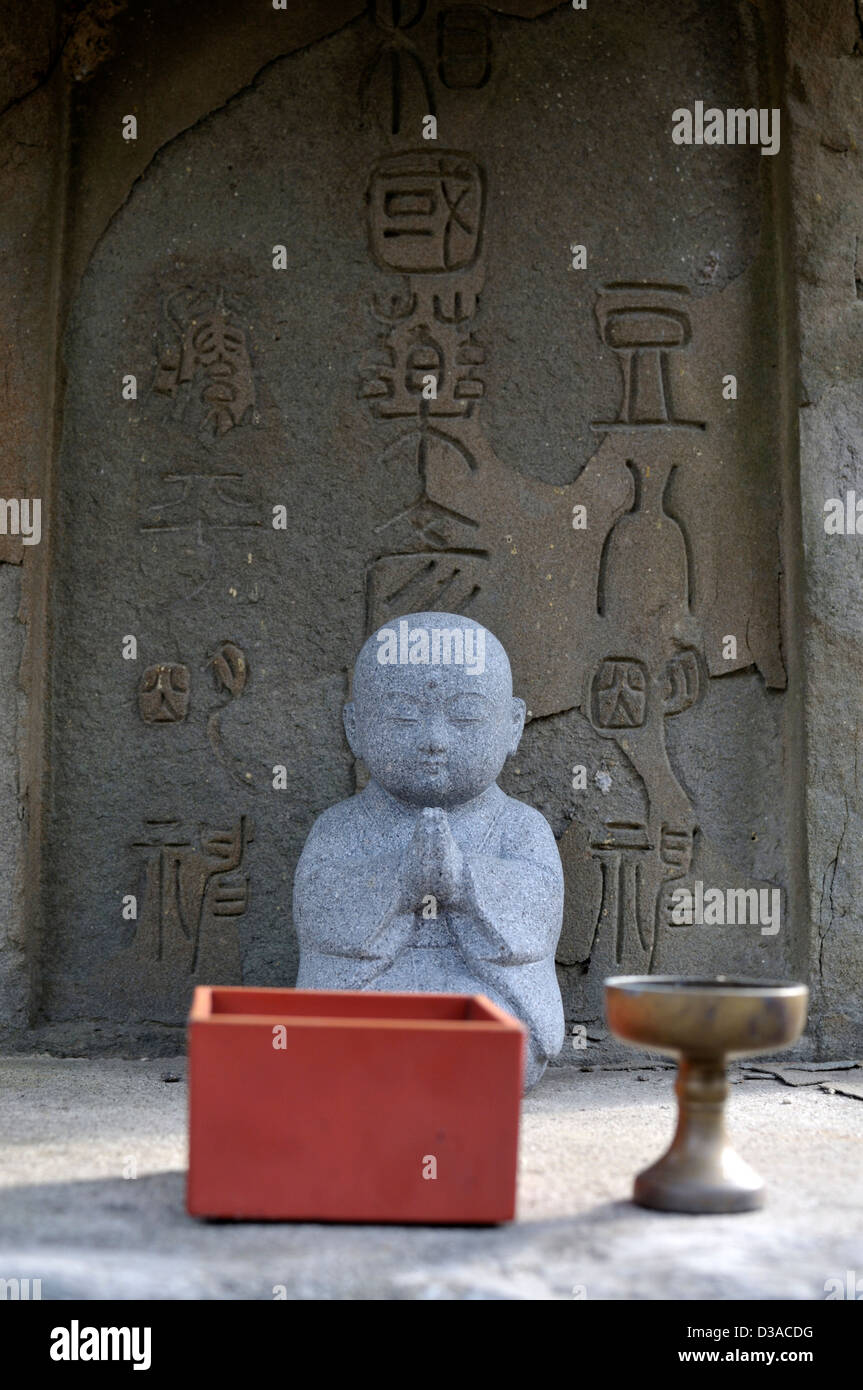 A small religious statue in a temple garden. A box and small tray ...