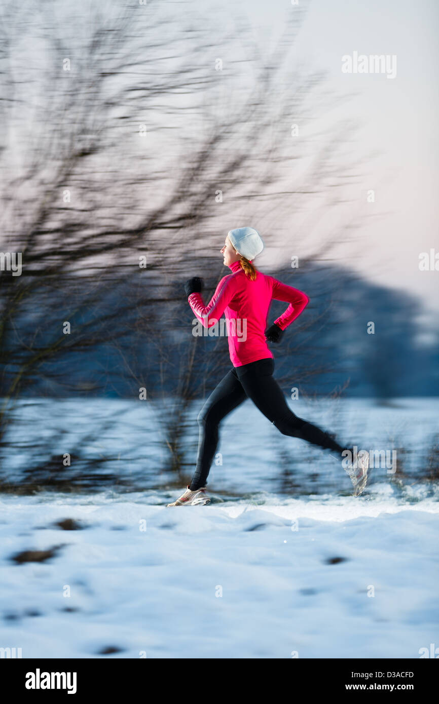 Young woman running outdoors on a cold winter day (motion blurred image ...