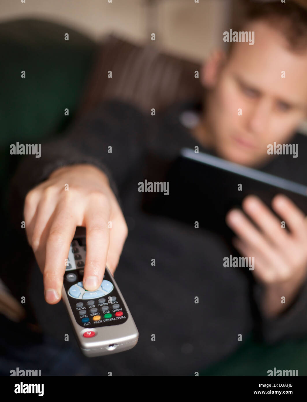 Youth with remote control lying on couch Stock Photo - Alamy