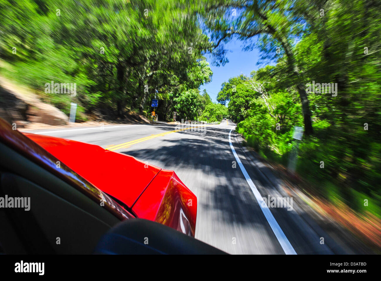 Photograph of a red sports car flying down a back country road with ...