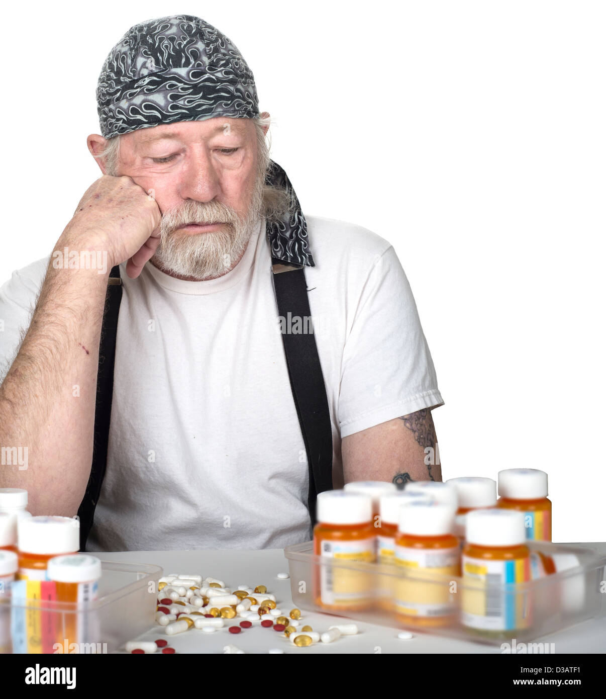 Senior staring down at a table with lots of prescription bottles and ...