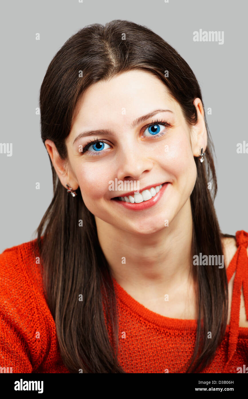 Portrait of a beautiful young woman smiling with red top over grey ...
